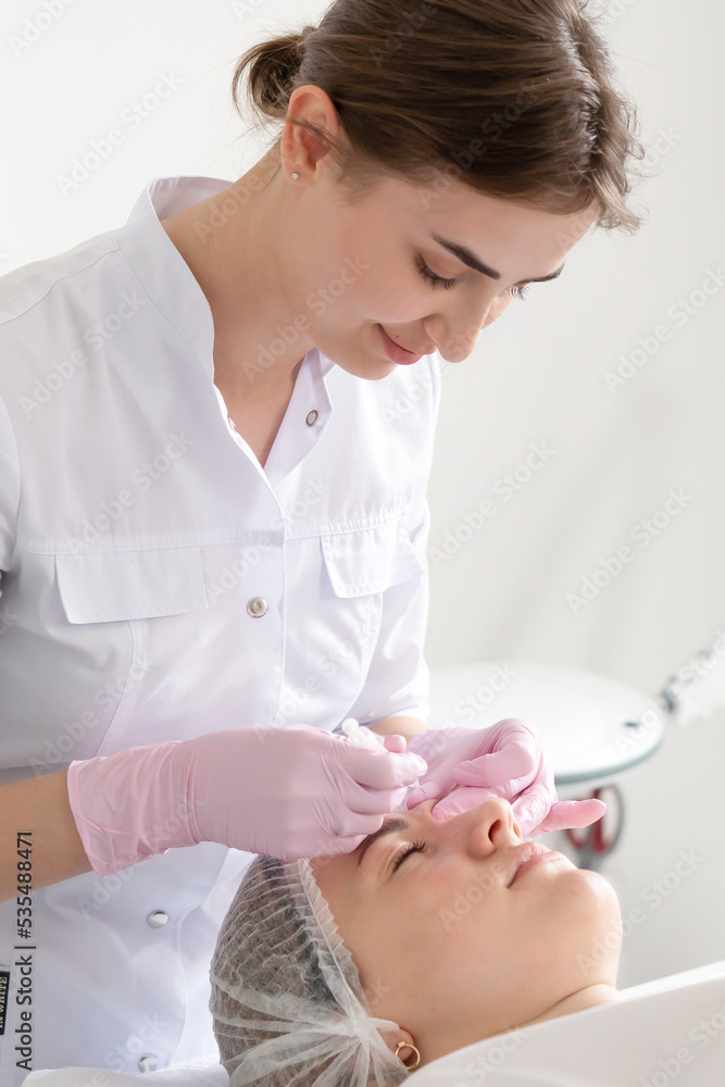 woman doctor cosmetologist dermatologist makes injections of botulinum ...