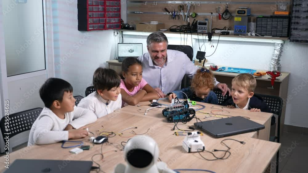 Zoom in group of multiracial kids watching at driven electric robotic ...