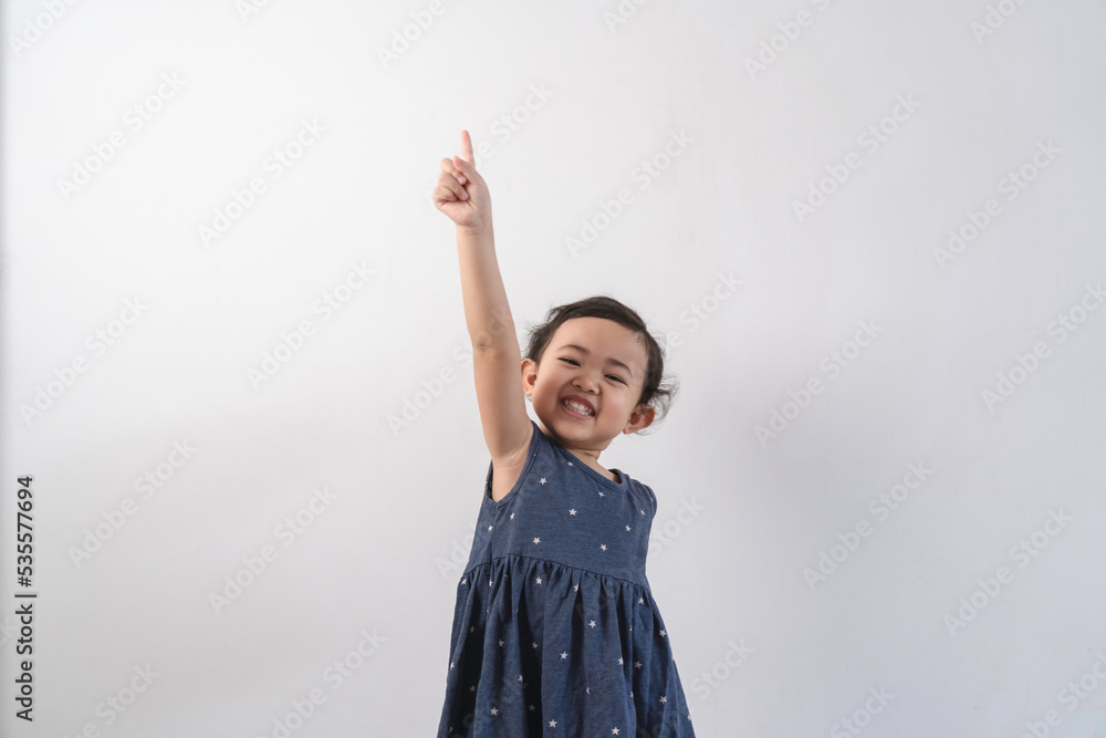 Happy smiling Asian child girl posing and pointing up isolated on white ...
