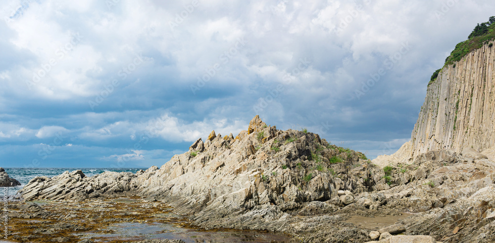 ocean shore with rocks of columnar basalt, Cape Stolbchaty on Kunashir ...