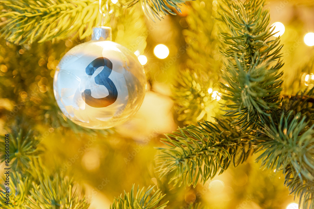 eine weiße Weihnachtskugel am Christbaum, mit einer Zahl (3) für den ... eine weiße Weihnachtskugel am Christbaum, mit einer Zahl (3) für den ...