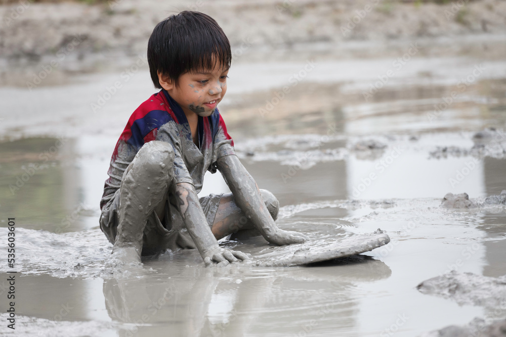 cute happy asian little boy enjoying to play in the mud at playground ...