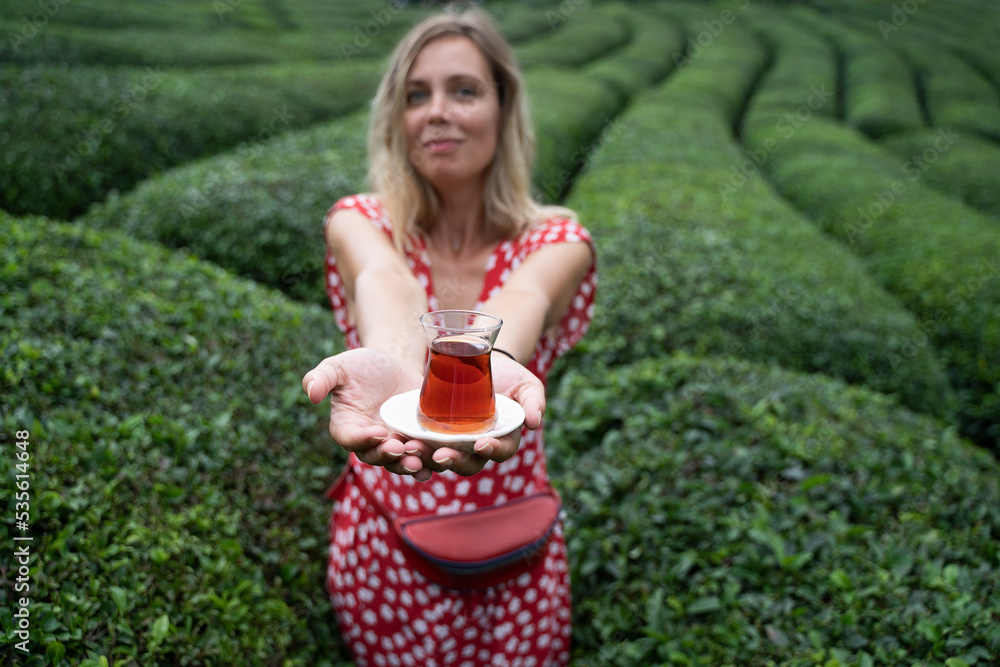 woman in red dress offering a traditional glass of fresh Turkish black ...
