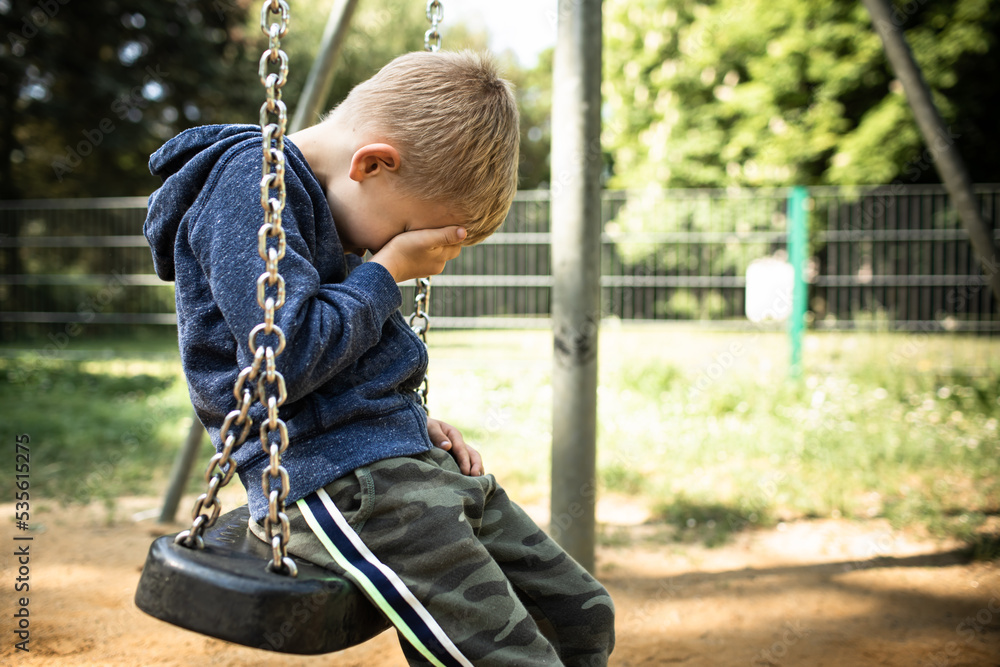 Sad little boy sitting on a swing Stock Photo | Adobe Stock