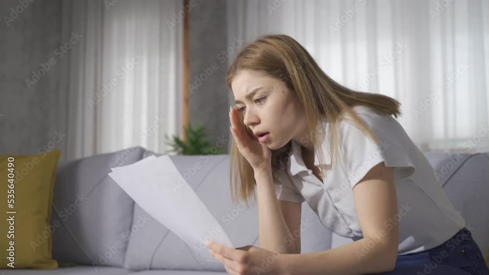 The young woman who is unhappy and saddened by the paper she is looking ...