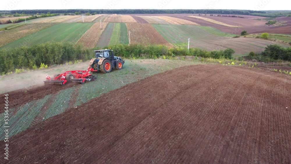 Aerial view of blue tractor plowing the field in beautiful sunset light ...