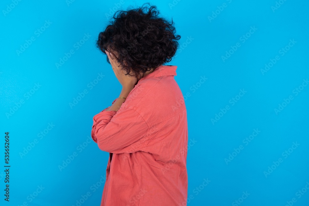 Sad young beautiful woman with curly short hair wearing red overshirt ...