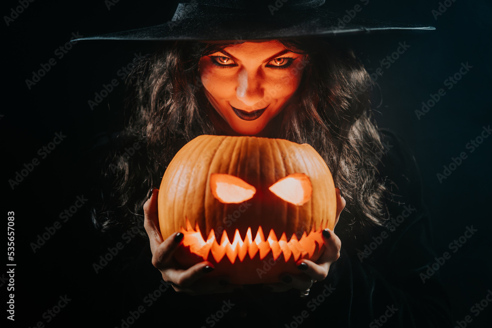 Mysterious black witch with pumpkin as head of jack-o-lantern on dark ...
