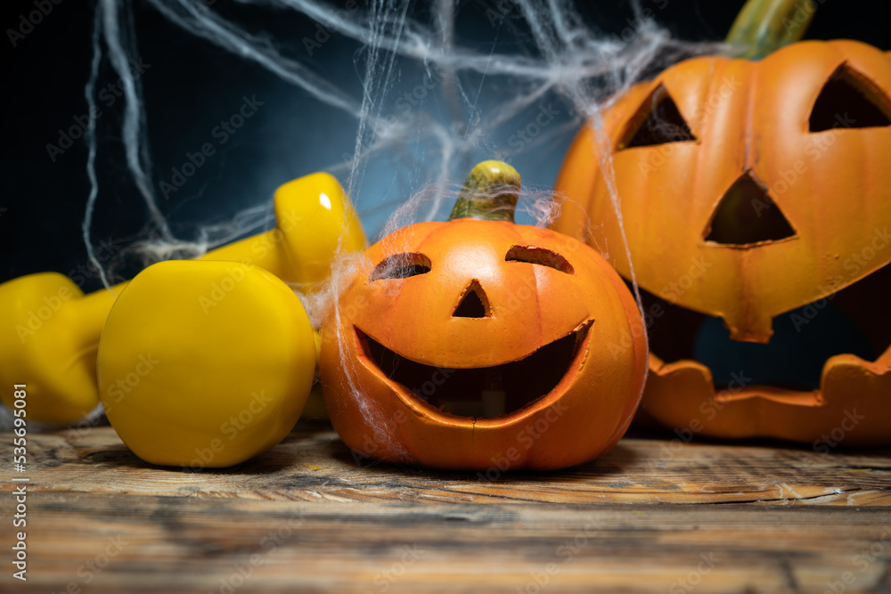 Yellow gym dumbbells and ceramic Halloween Jack-o'-lantern spooky ...