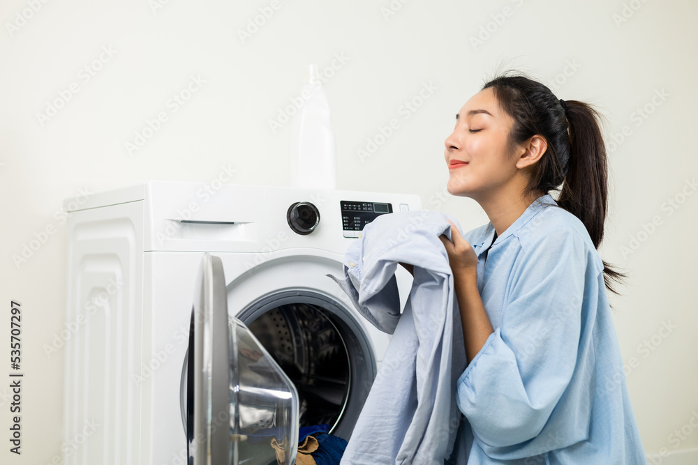 Happy housewife opens the front of the washing machine and smiles to ...