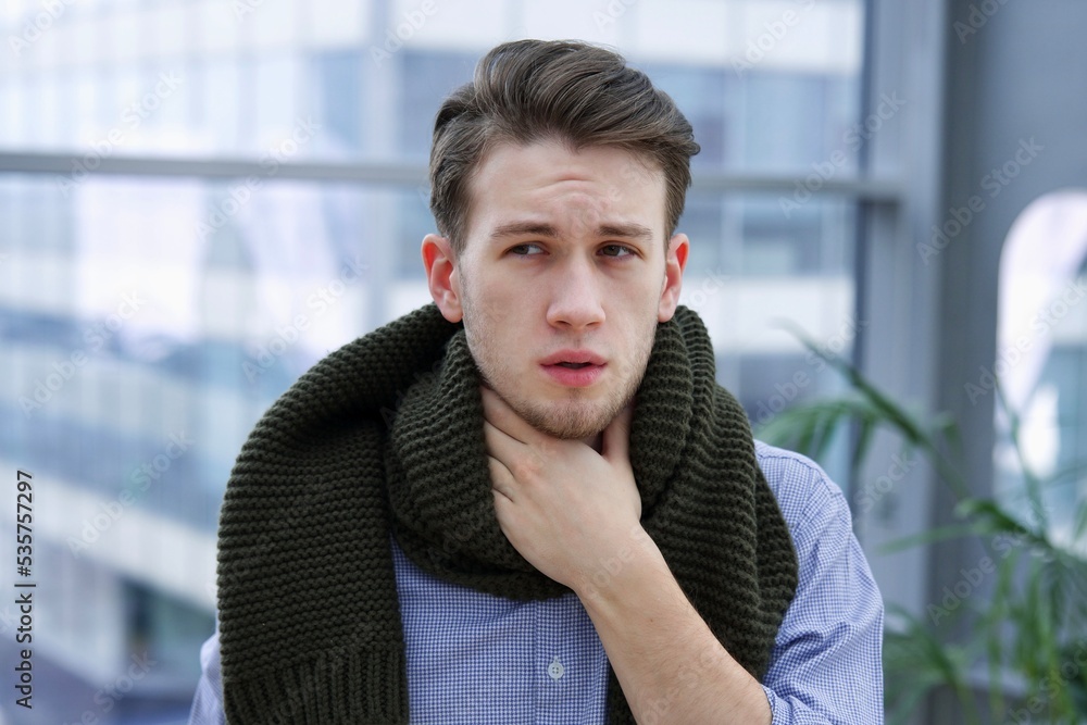 Sick ill guy, young man suffering from pain in throat. Boy in scarf is ...