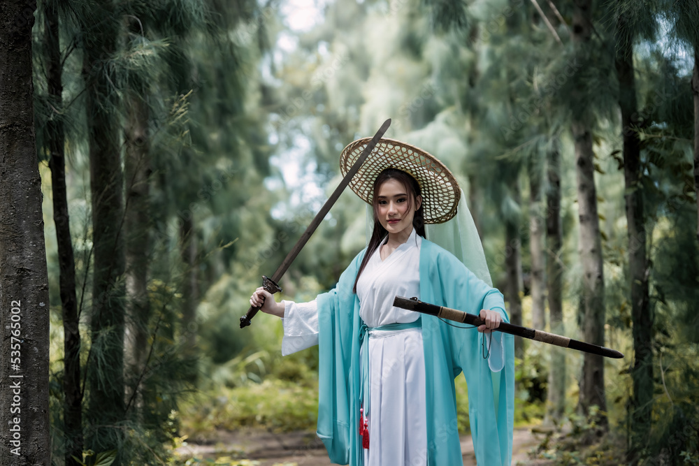 Portrait woman in a Chinese costume with a sword in the forest. Chinese ...