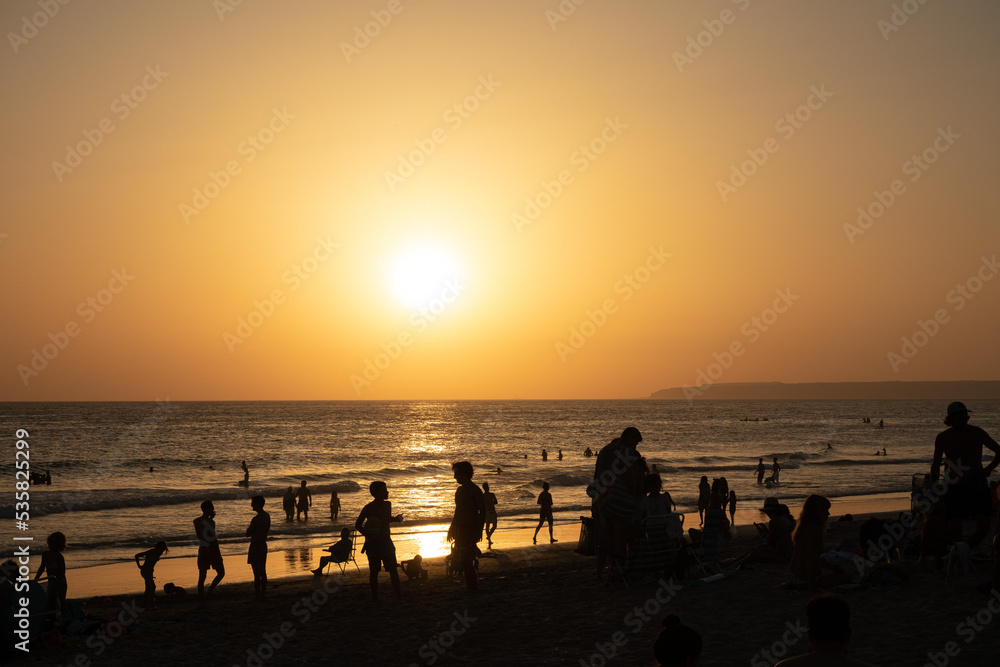 Foto de un atardecer en la playa a contraluz. Se ven siluetas de ...