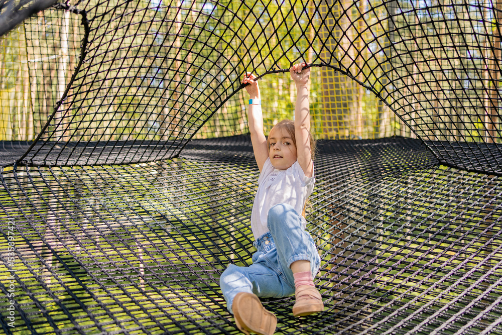 child having fun in net tunnel in playground or amusement park. Stock ...