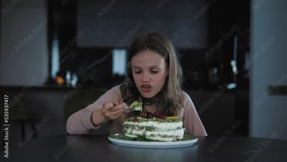 Hungry funny kid female eating birthday cake alone, having fun, dancing ...