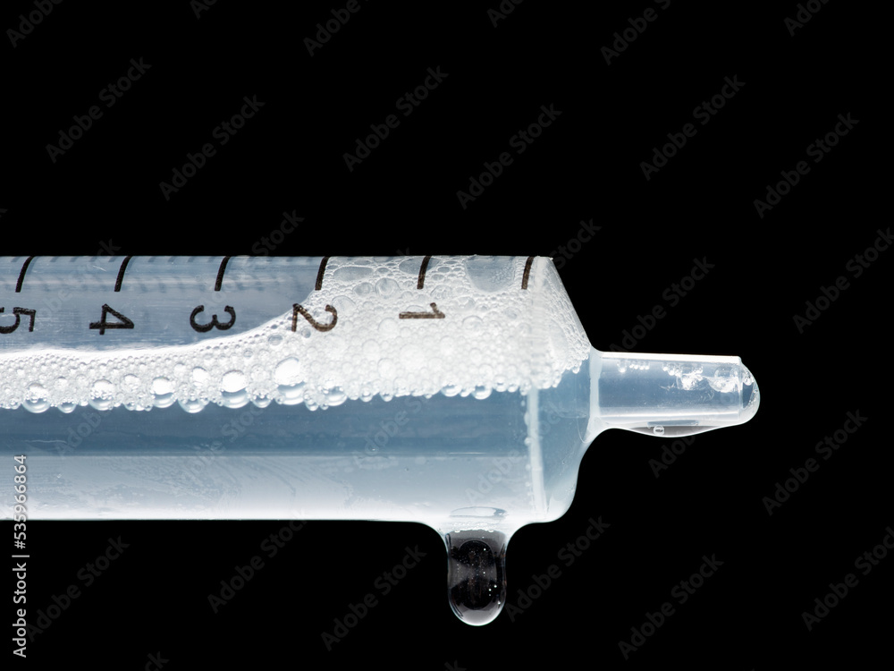 Medical syringe showing liquid bubbling and dripping has its expelled ...