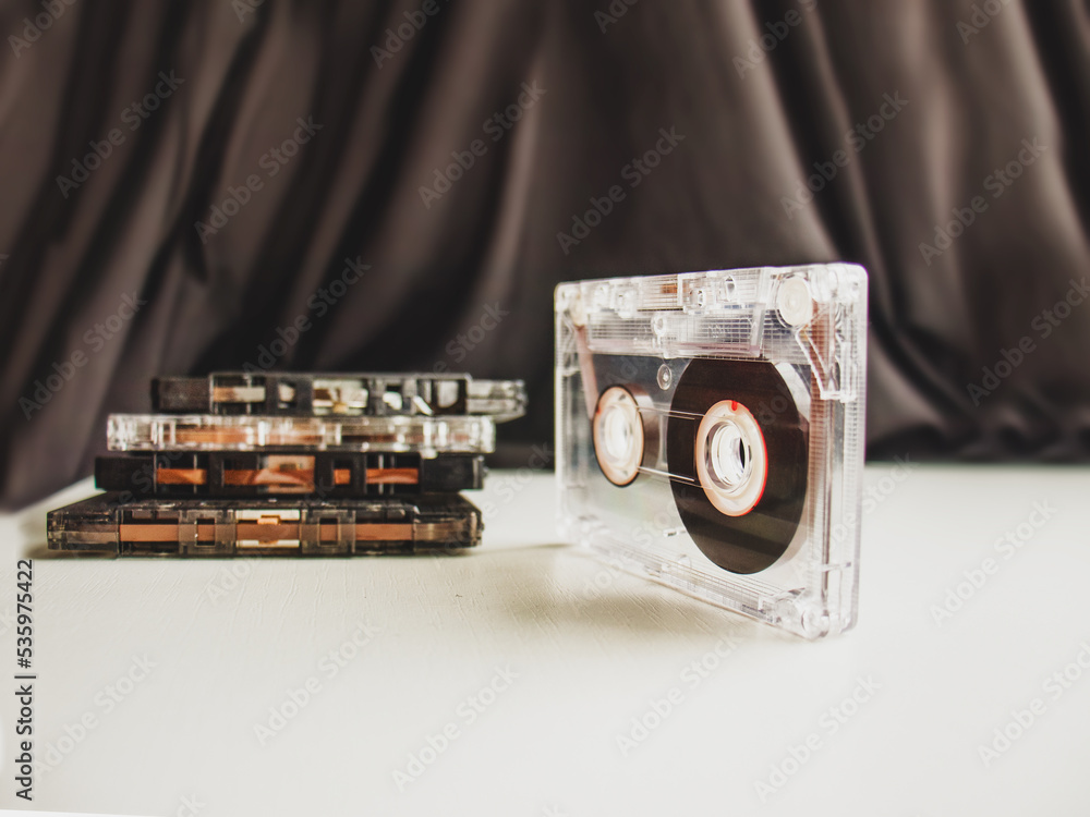audio cassette and stack of cassettes on table against dark background ...