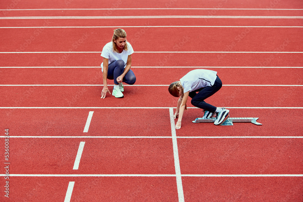 Female coach training athlete. Fit girl getting ready to run on ...