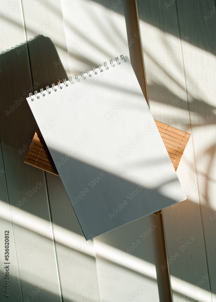 An open blank notepad is on a wooden crate on a white table. The ...