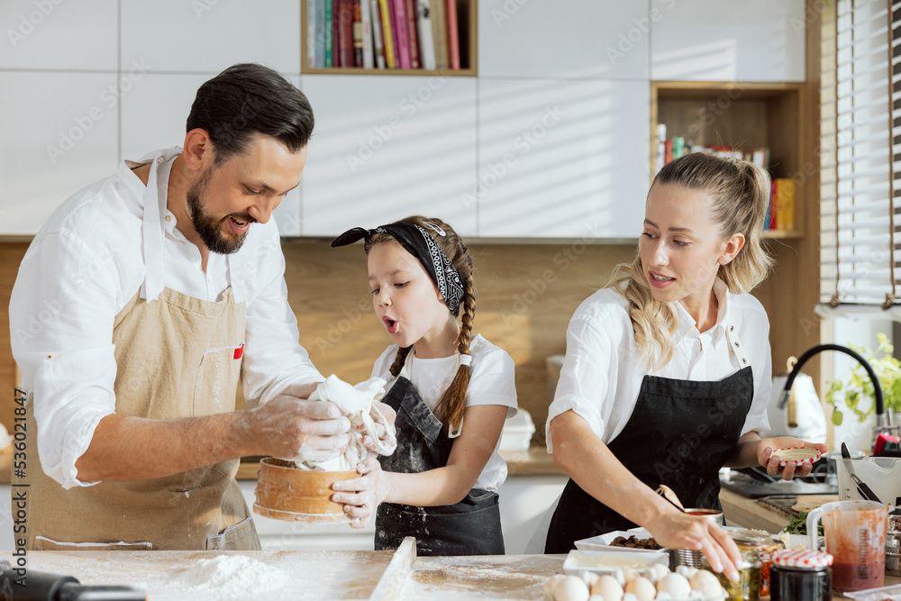 Curious daughter holding sive above wooden surface happy father pouring ...