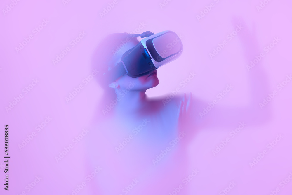 Female model in VR goggles immersed in clouds of smoke, fog on a pink ...