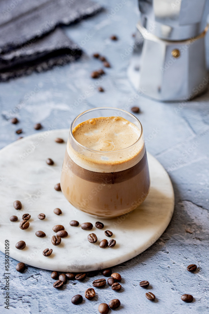 Ice cold coffee brew in a Moka pot on a marble round tray on a blue ...