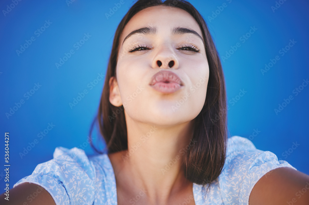 Taking a selfie, kiss and portrait of girl on blue background with ...