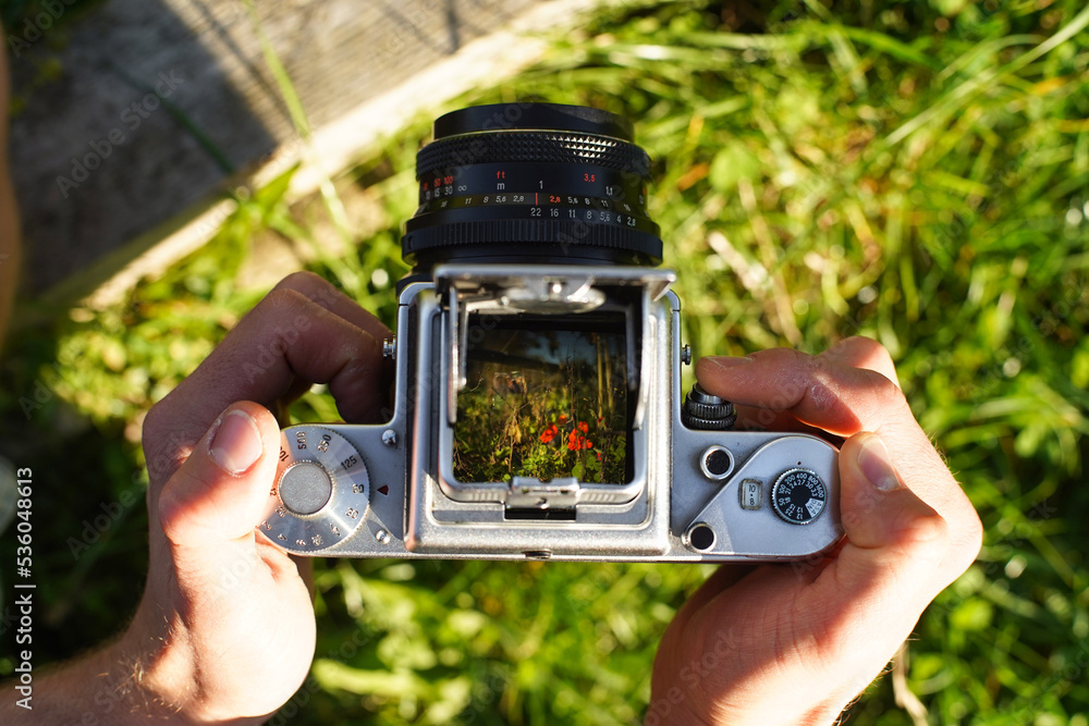 A photographer holding a vintage analog photo camera focusing ajusting ...