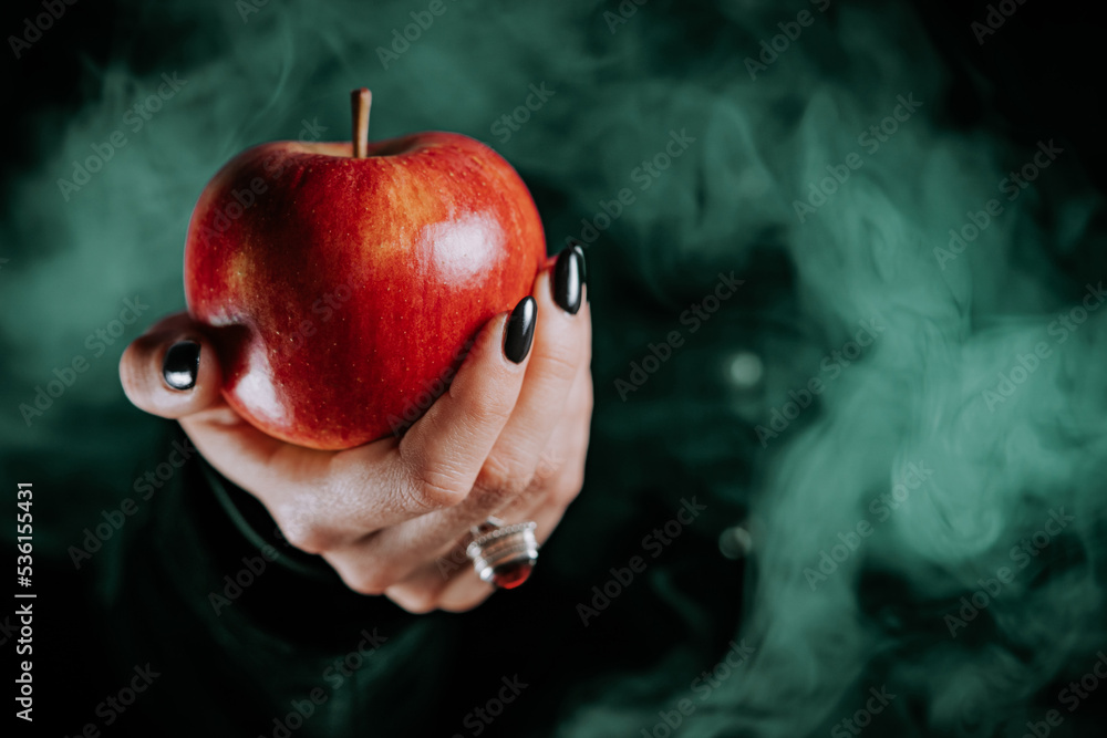 Woman as witch offers red apple as symbol of temptation, poison. Fairy tale, white snow wizard ...