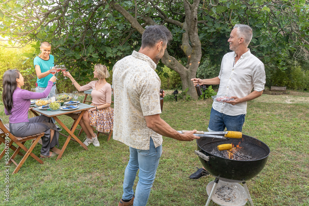 Friends cooking with the barbecue having a conversation smiling happy ...