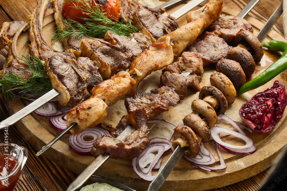 Shashlik from different meats on barbecue skewers with vegetables and ...