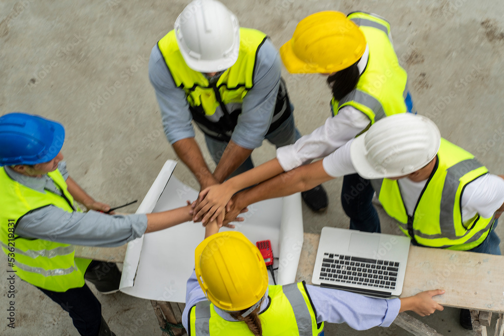 Five workers wearing helmets to ensure safety at work, all join hands ...
