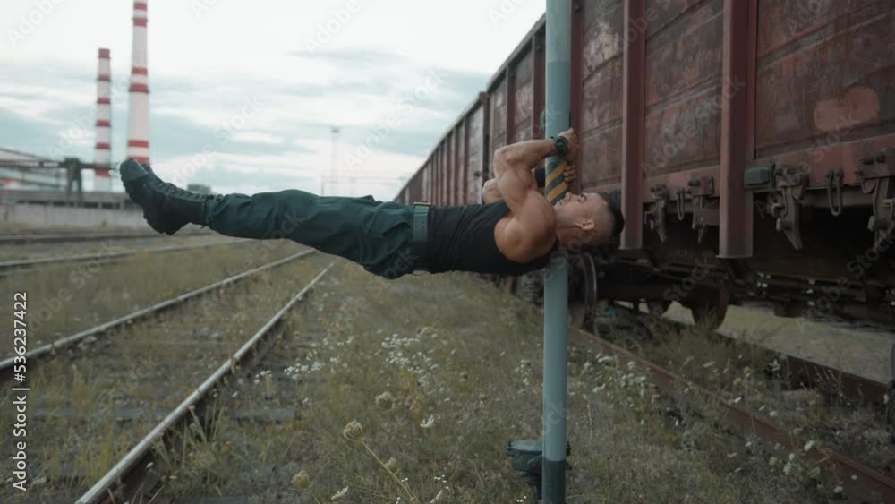 Vidéo Stock Bodybuilder training at railway yard near a factory and ...
