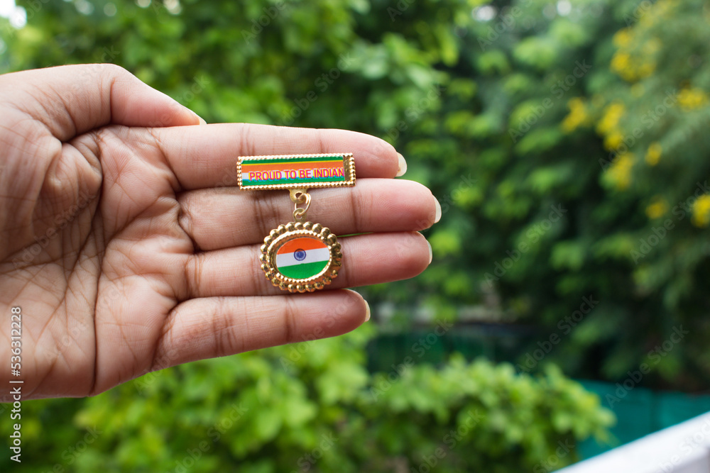 A girl or woman holding a metal badge with Indian flag colors and ...