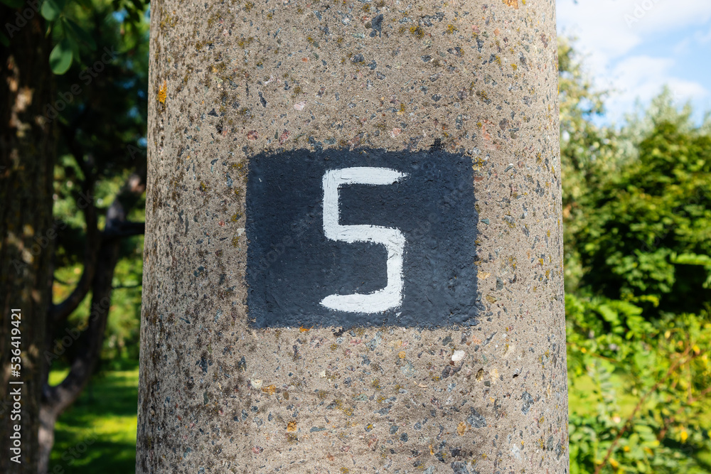The number five stencil on the surface of a concrete pillar. Numeral 5 ...