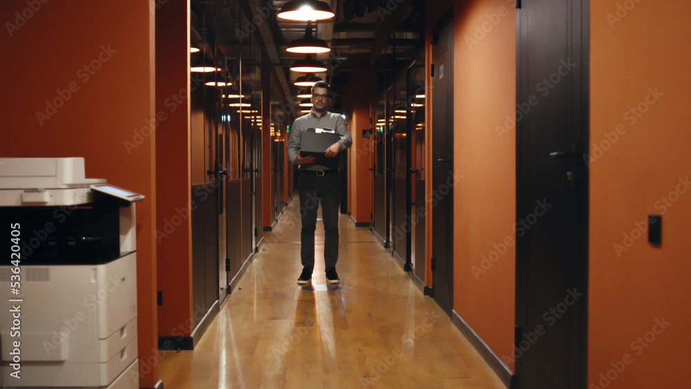 Fired upset man in suit walking down in office hallway, holding box ...