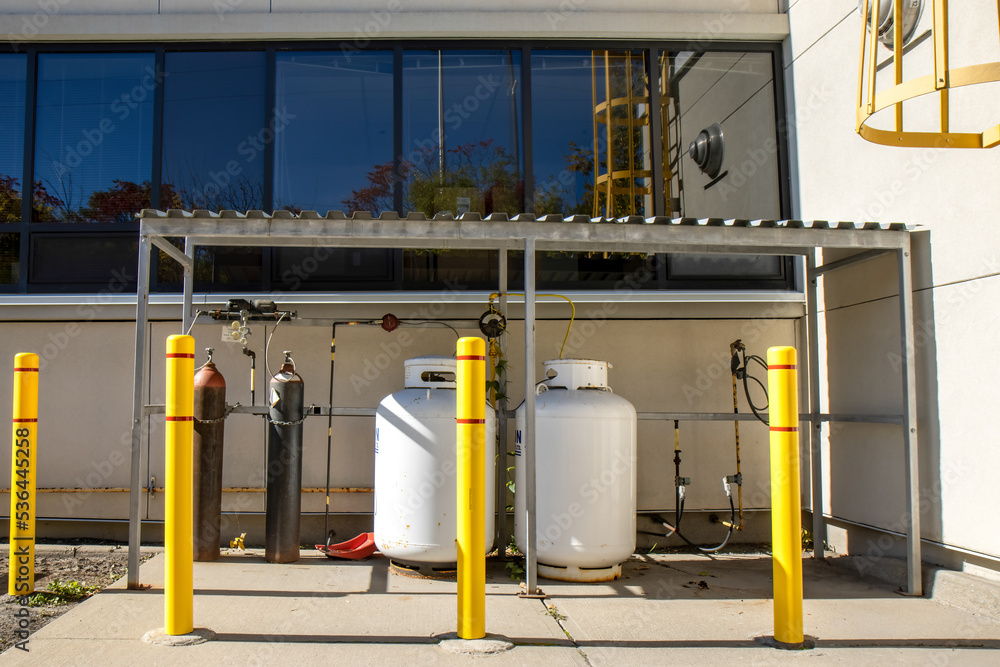 Exterior two white propane tanks and two compressed gas cylinders ...