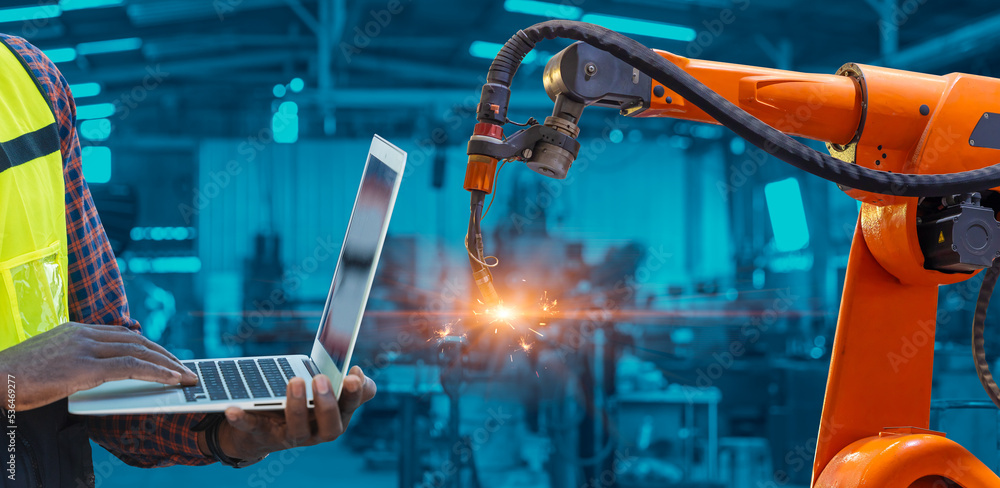 Engineer worker using laptop computer program control Robotic Arm ...