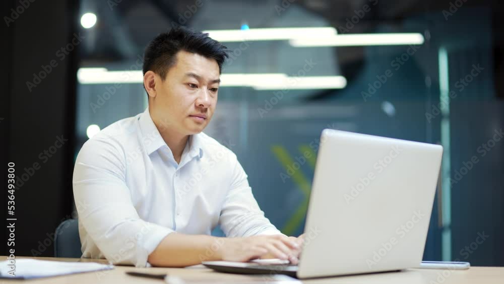 Bored asian office worker sitting at work workplace at computer desk ...