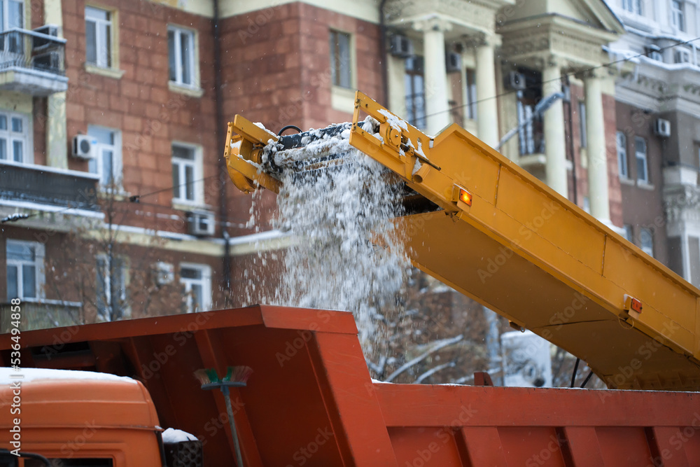 Snow cleaning tractor (snow-removal machine) loading pile of snow on a ...