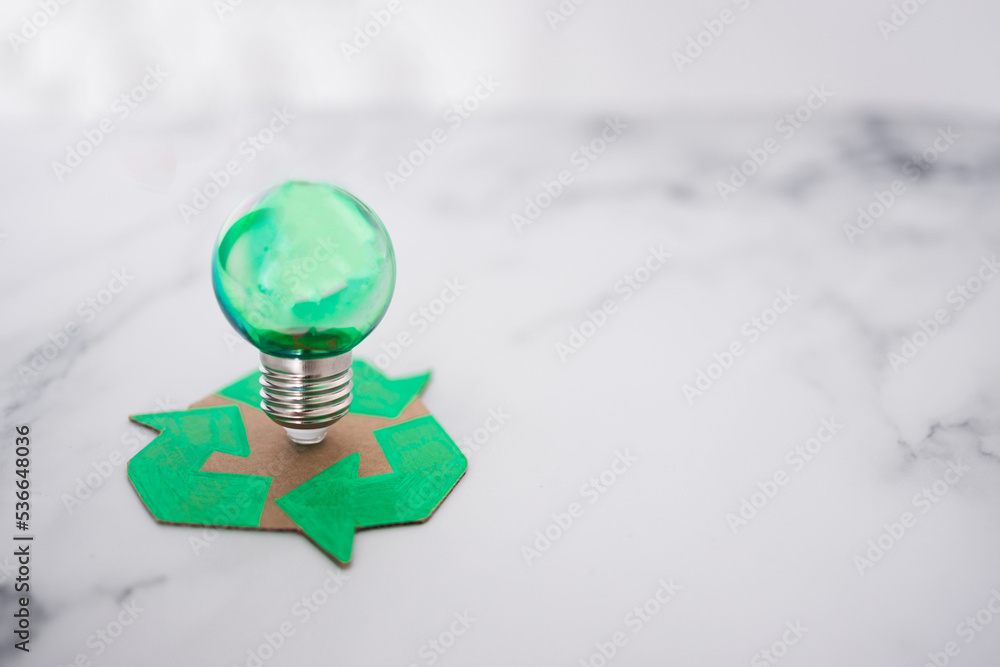 recycle sign with green light bulb standing on it, concept of ...