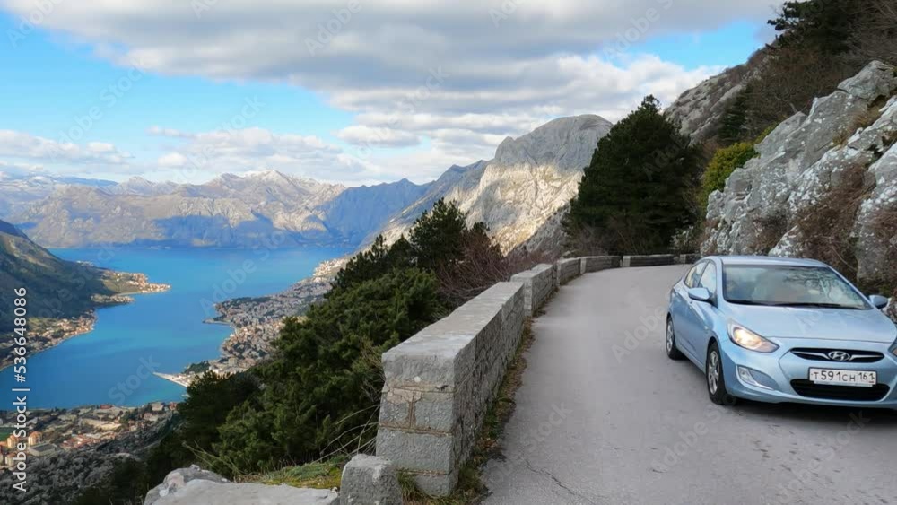 Car slowly drives along narrow mountain road, fenced with parapet of ...