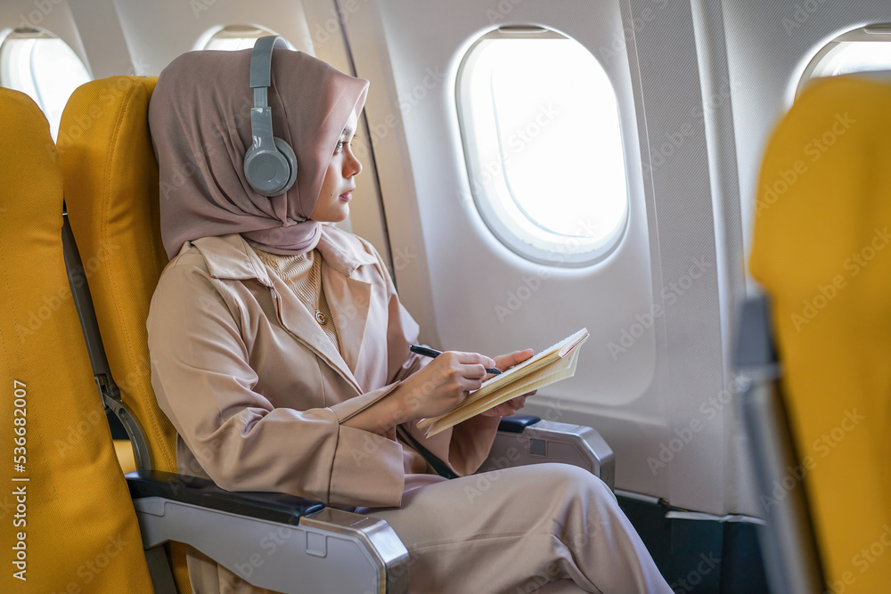 Beautiful asian muslim woman passengers wearing wireless headphone and ...