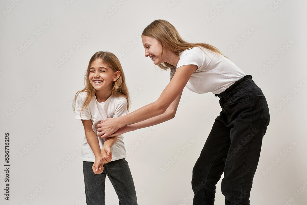 Teenage girl tickling her little sister on white Stock Photo | Adobe Stock