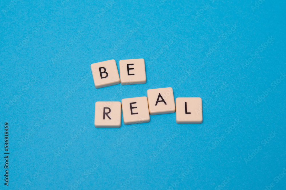 Be real text with plastic letters on blue paper sheet. Popular and ...
