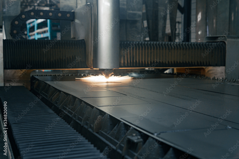 heavy industrial laser cutter during metal sheet processing, head with ...