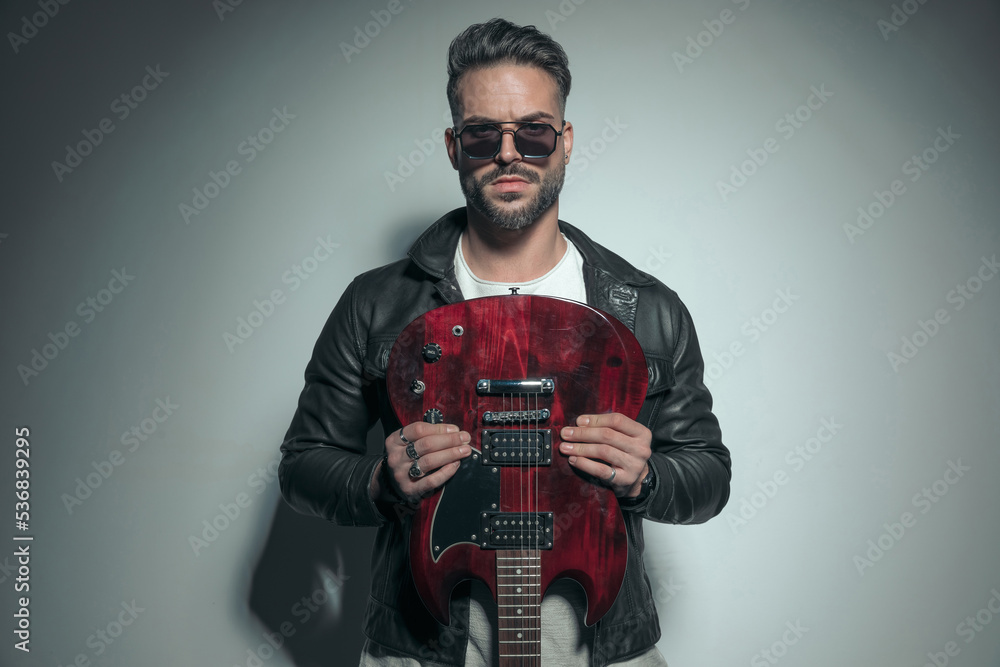 handsome rock singer holding his electric guitar upside down Stock ...