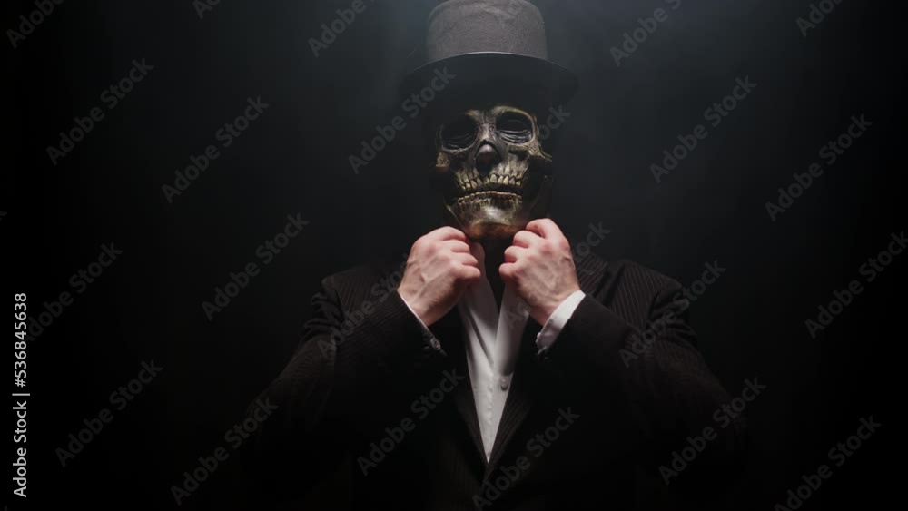 Man in skeleton suit in black jacket comes out of darkness and adjusts ...