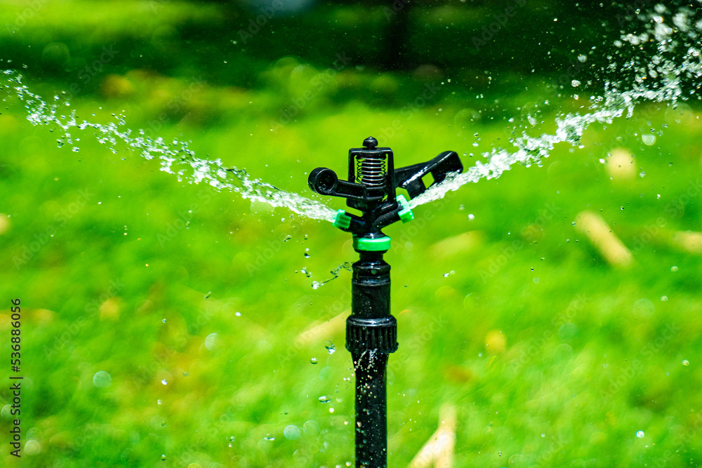 fresh water splash from the sprinkle pole settle in the grass feild in ...