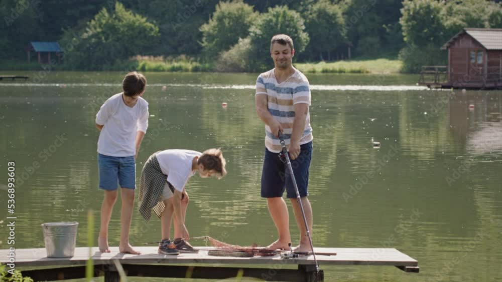 Father fishes and sons help gather fish with excitement. Father fishes ...
